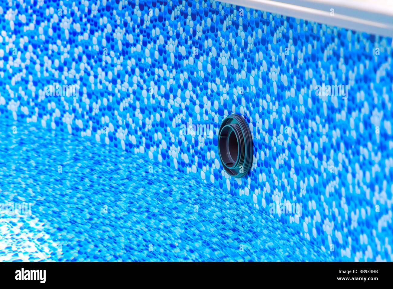 Bright blue mosaic design of pool liner reveals drainage opening in ...