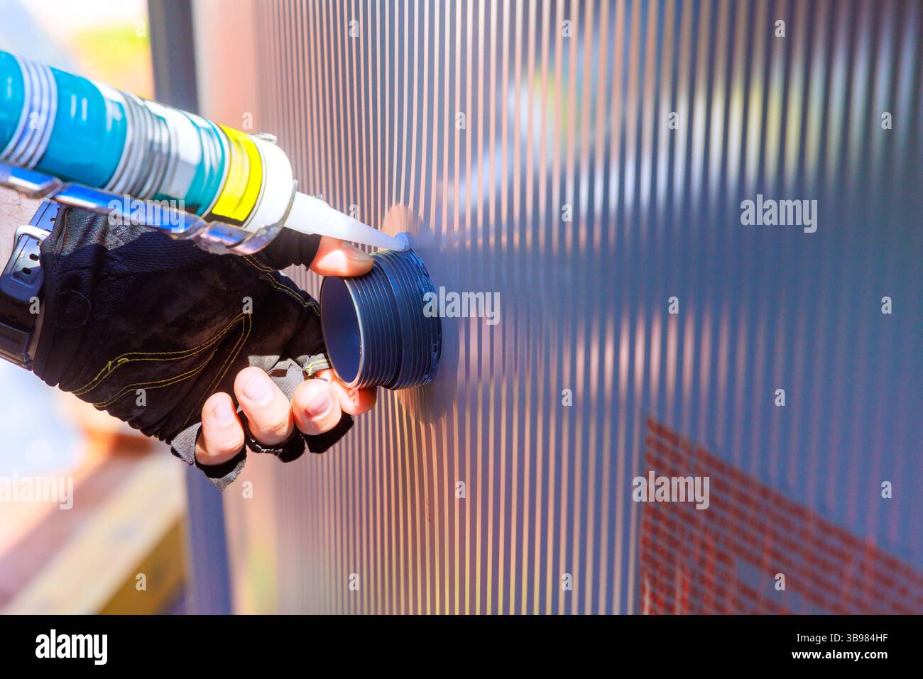 Worker seals connection on pool liner with caulking gun at construction ...