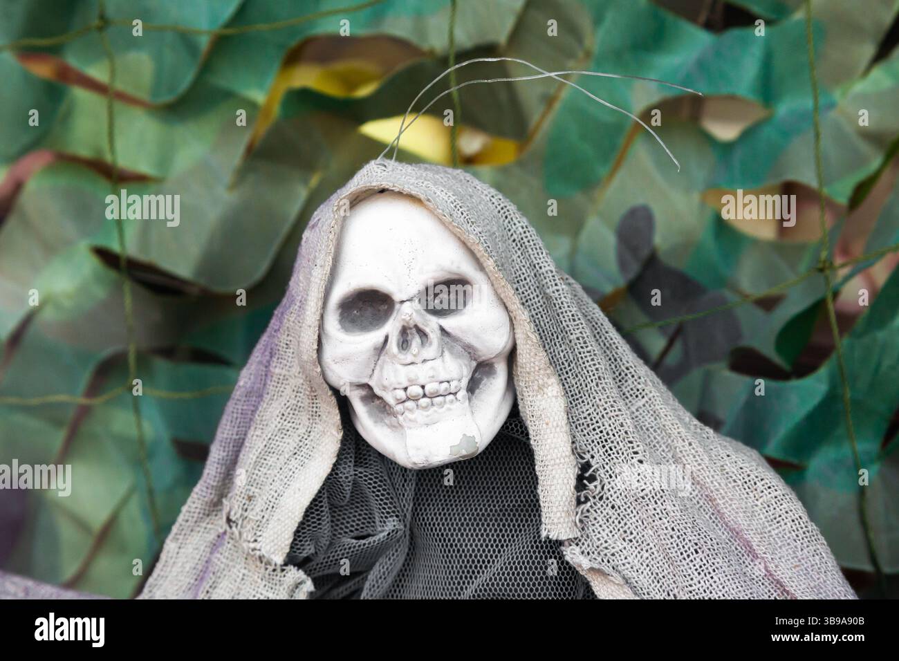 A figurine of death in the form of a human skull with a hood on a ...