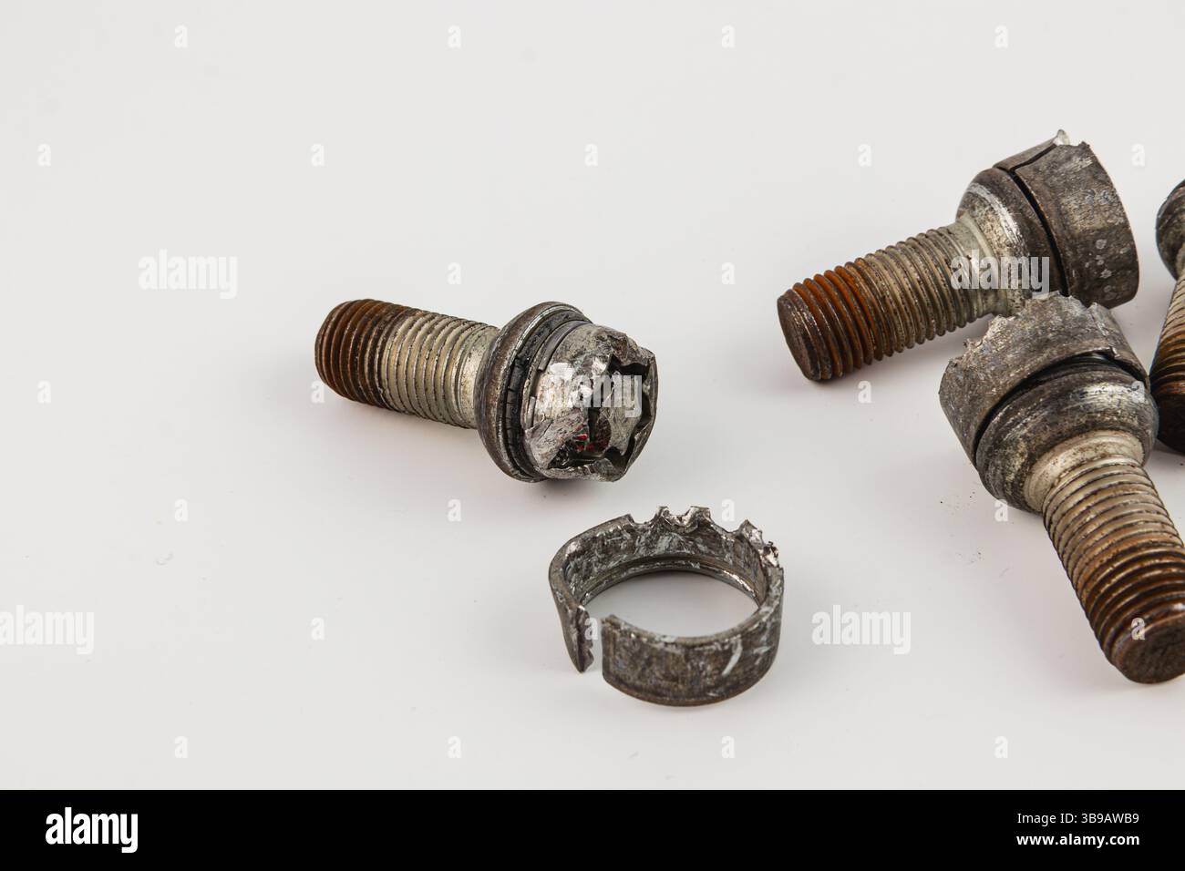 Rusty metal bolts and a retaining ring are displayed on a plain surface ...