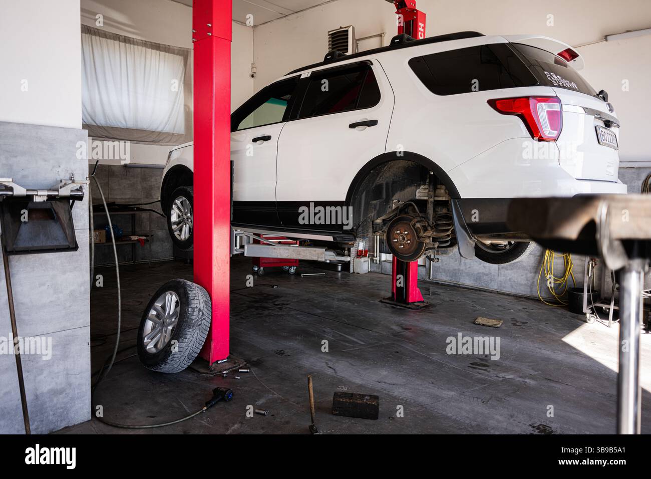 Kyiv, Ukraine - May 02, 2025: White Ford Explorer SUV raised on hydraulic lift inside a clean ...