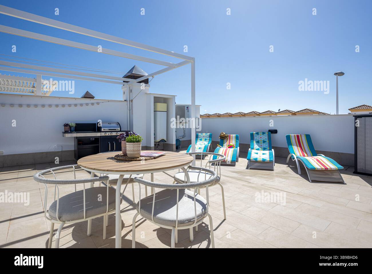 Spacious rooftop terrace with colorful sun loungers, outdoor dining set ...