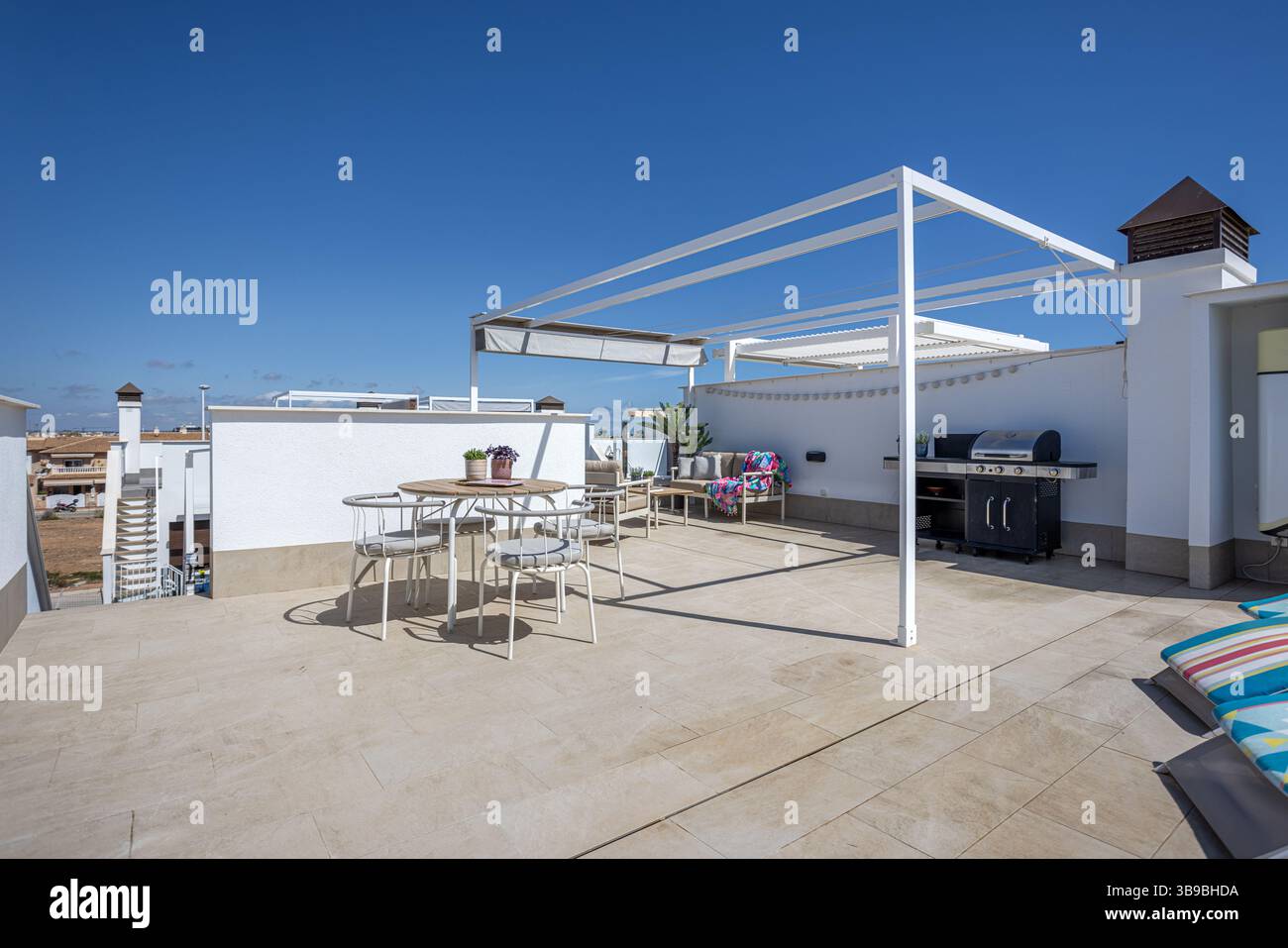 Modern rooftop space featuring a barbecue station, round dining table ...