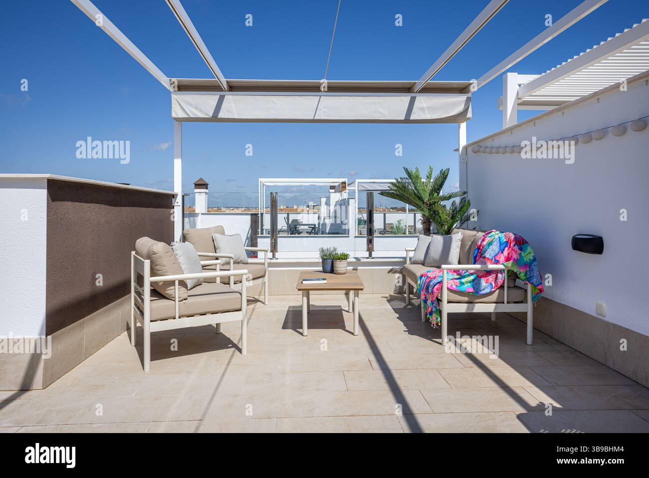 Comfortable rooftop corner with beige cushioned armchairs, coffee table ...