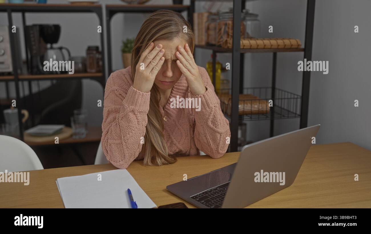 Woman stressed in office with hands on head sitting at desk surrounded ...