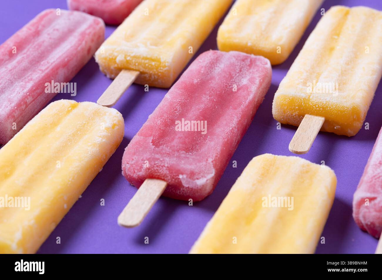 Red strawberry popsicles and yellow popsicles on purple background ...