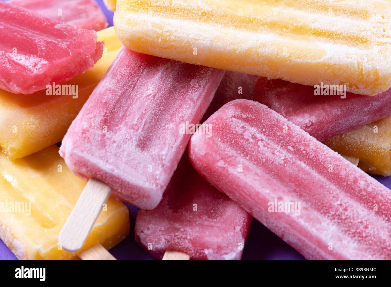 Red strawberry popsicles and yellow popsicles on purple background ...