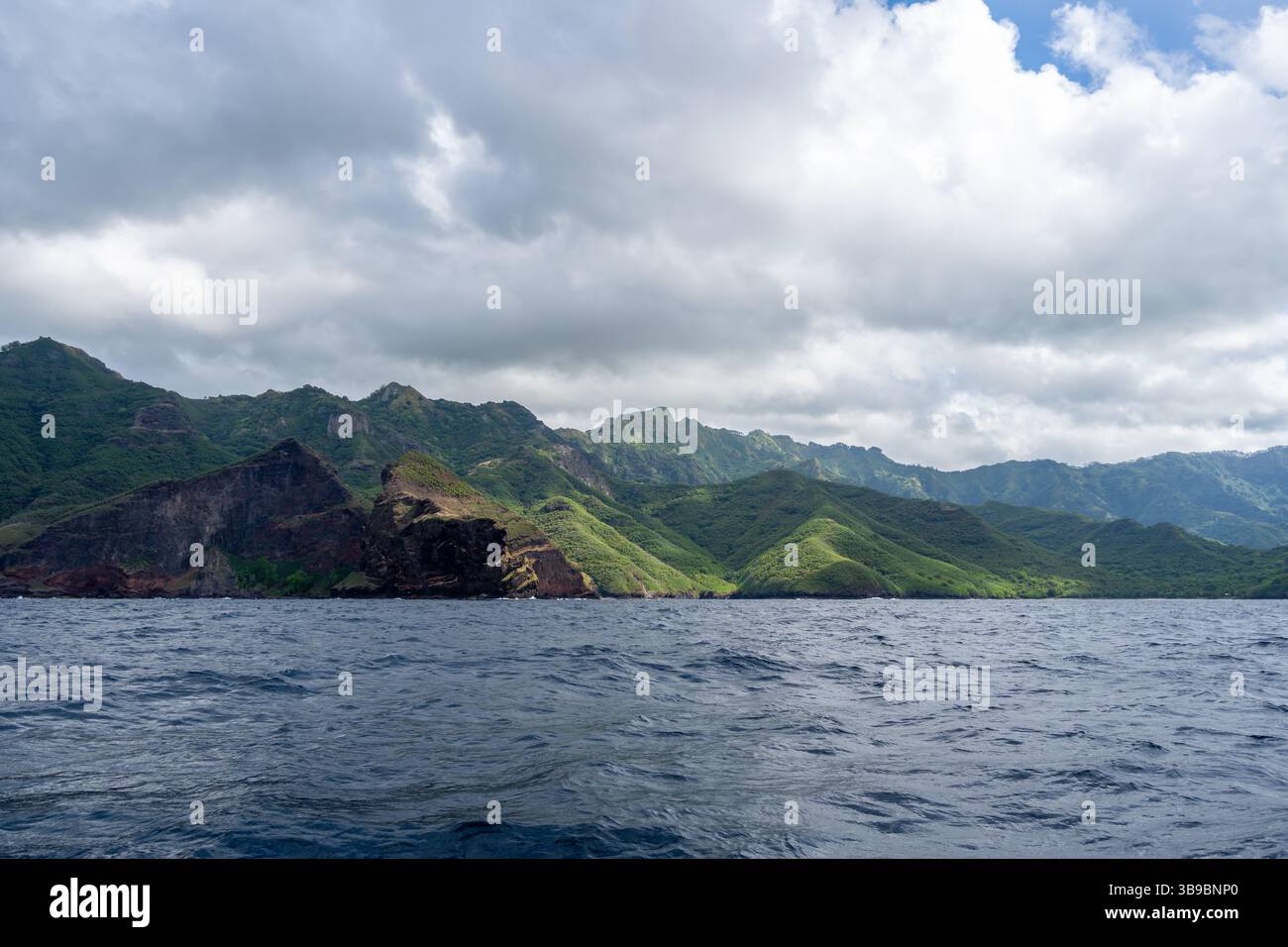 Green cliffs rise above the ocean along the rugged coastline between ...
