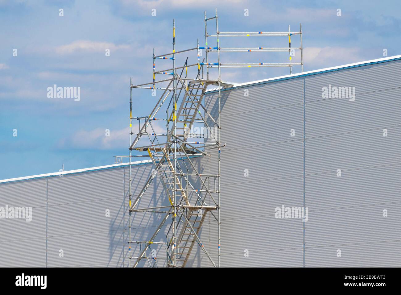 Scaffolding on industrial warehouse against cloudy sky Stock Photo - Alamy
