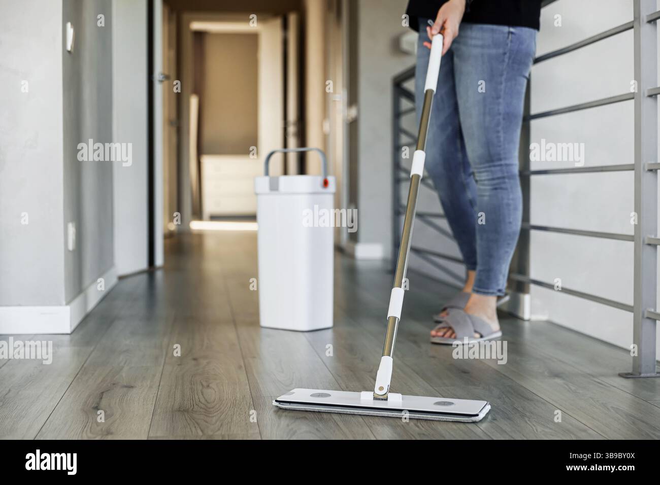 Woman mopping, wiping sleek hardwood floor in modern home setting ...
