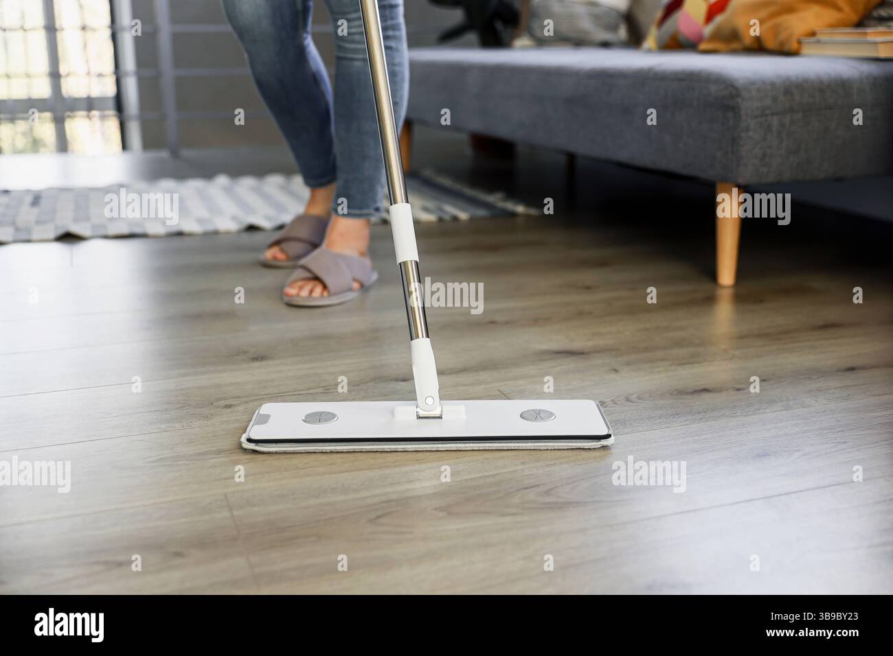Woman mopping, wiping sleek hardwood floor in modern home setting ...