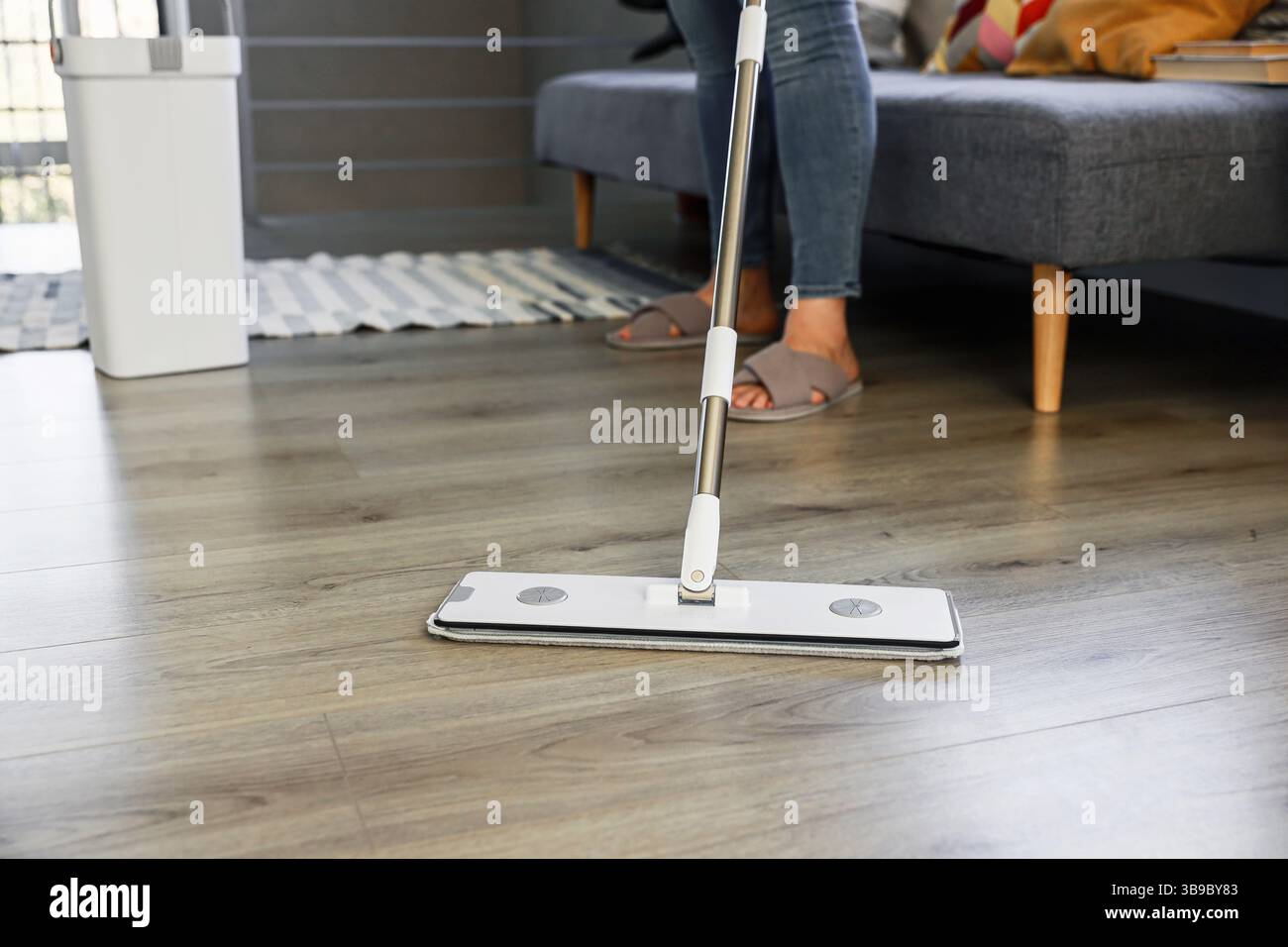 Woman mopping, wiping sleek hardwood floor in modern home setting ...