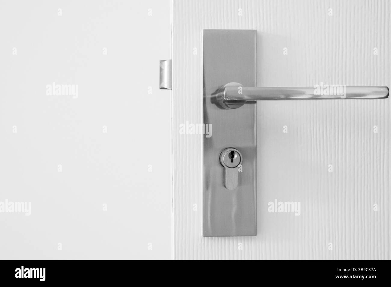 Modern door handle with keyhole on white door Stock Photo - Alamy