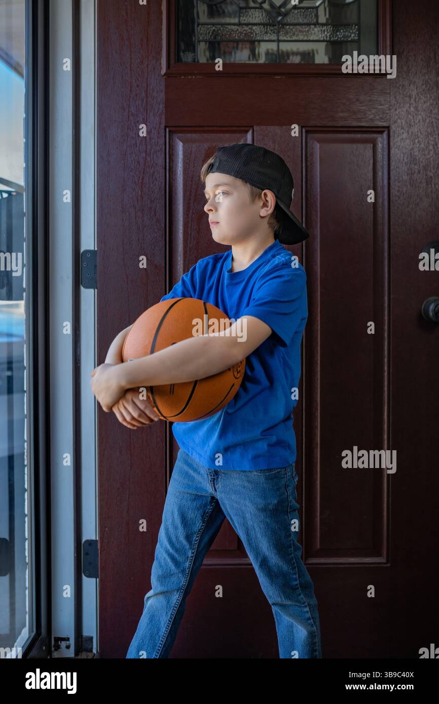 boy holding a basketball and staring out front door Stock Photo - Alamy
