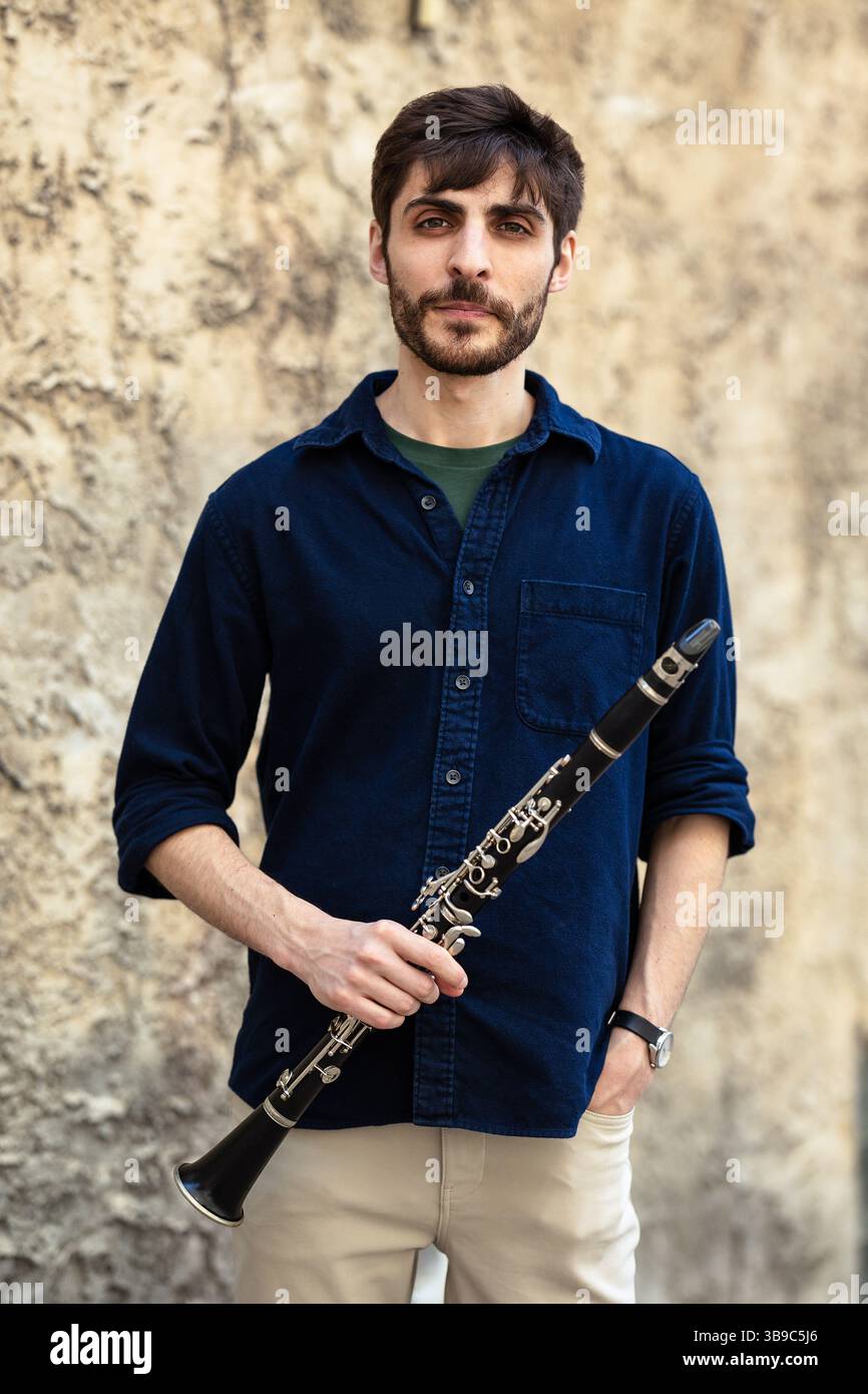 a man with dark hair wearing a flannel holding a clarinet Stock Photo ...