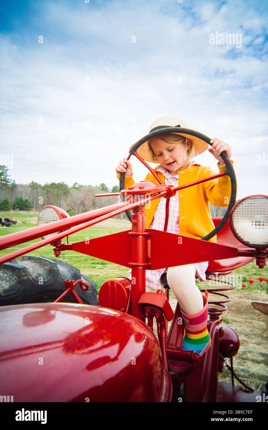 Young girl riding red tractor Stock Photo - Alamy