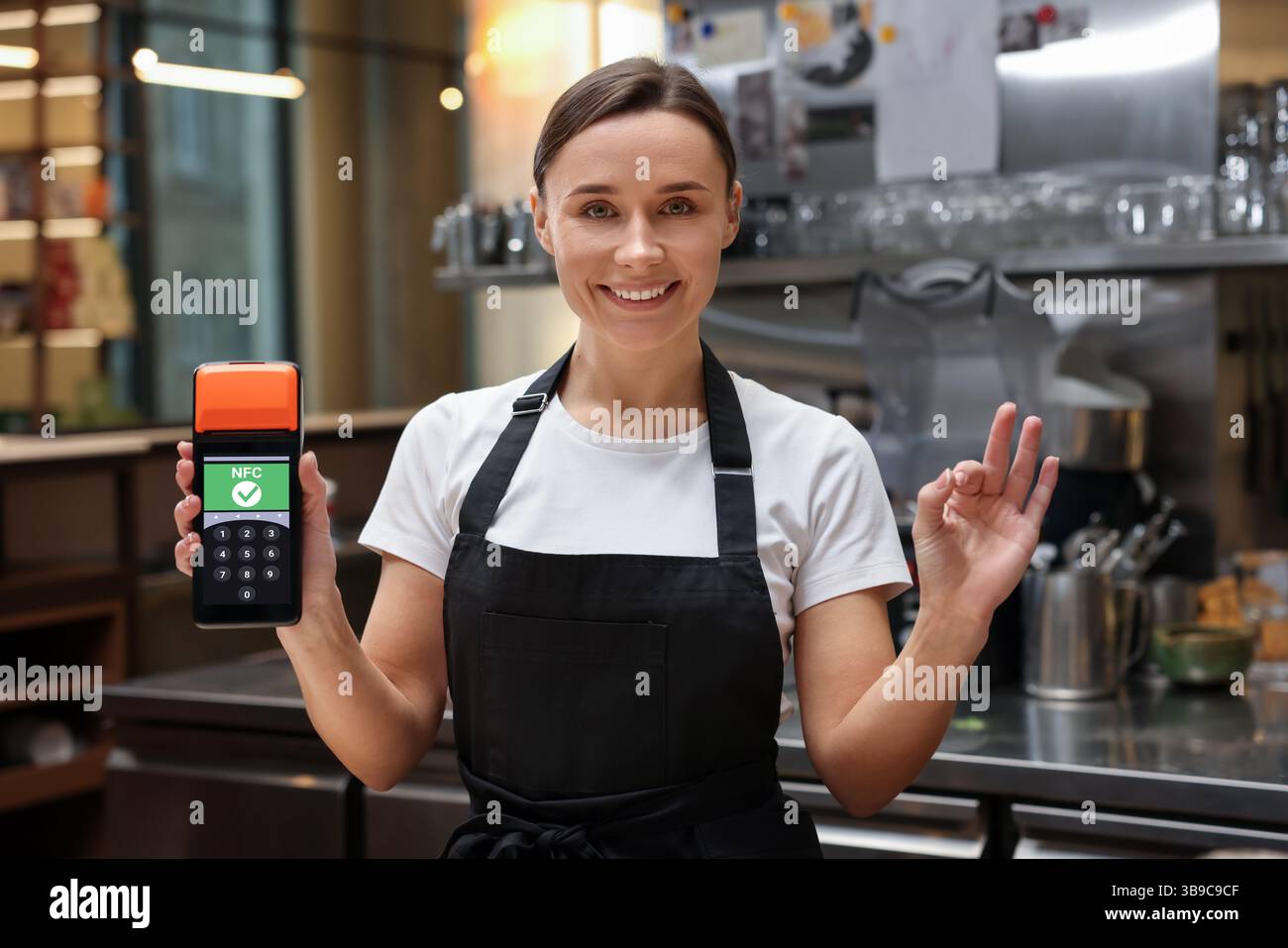 Woman holding payment terminal with NFC system and showing ok in ...