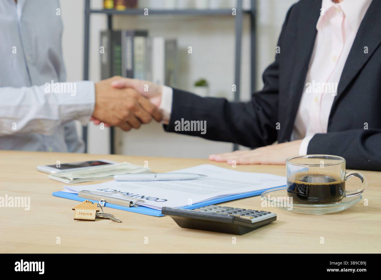 Estate agent shaking hand with client after signing agreement contract ...