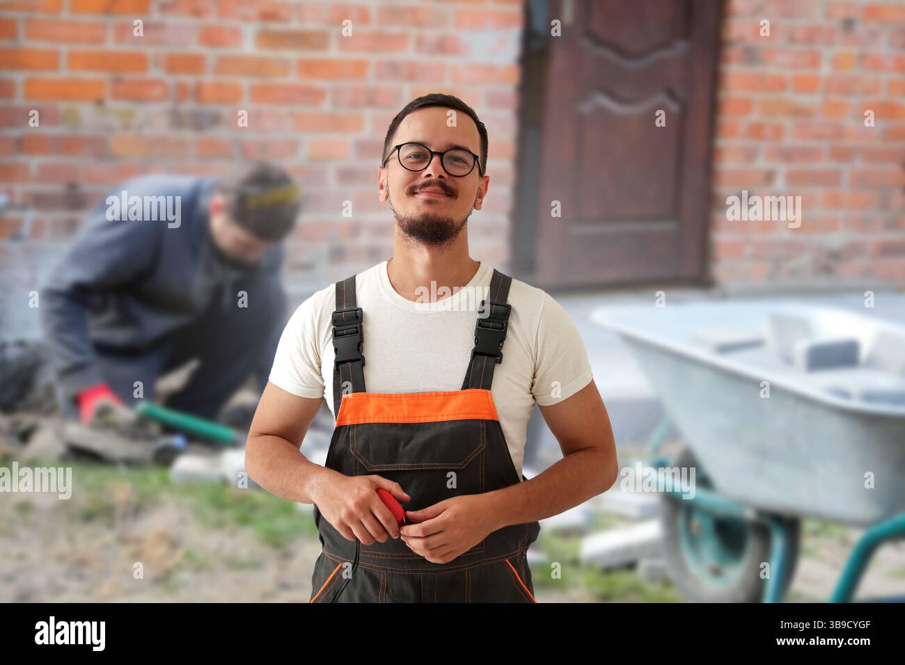Smiling construction worker in overalls with a tape measure, building a ...