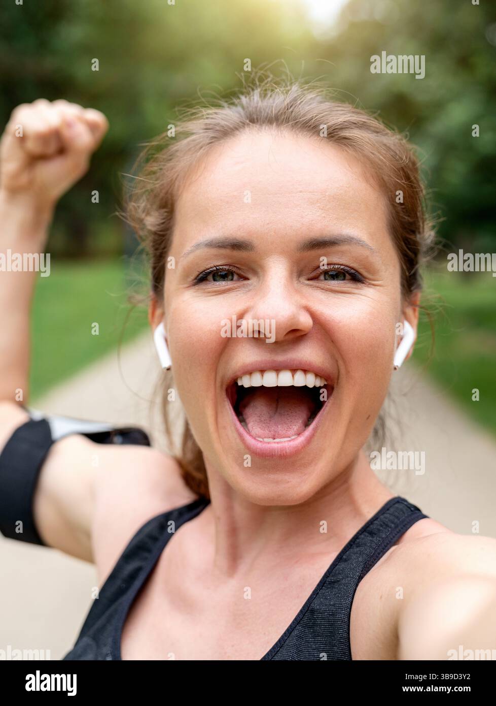 Excited woman flexing muscles and taking selfie after completing street ...