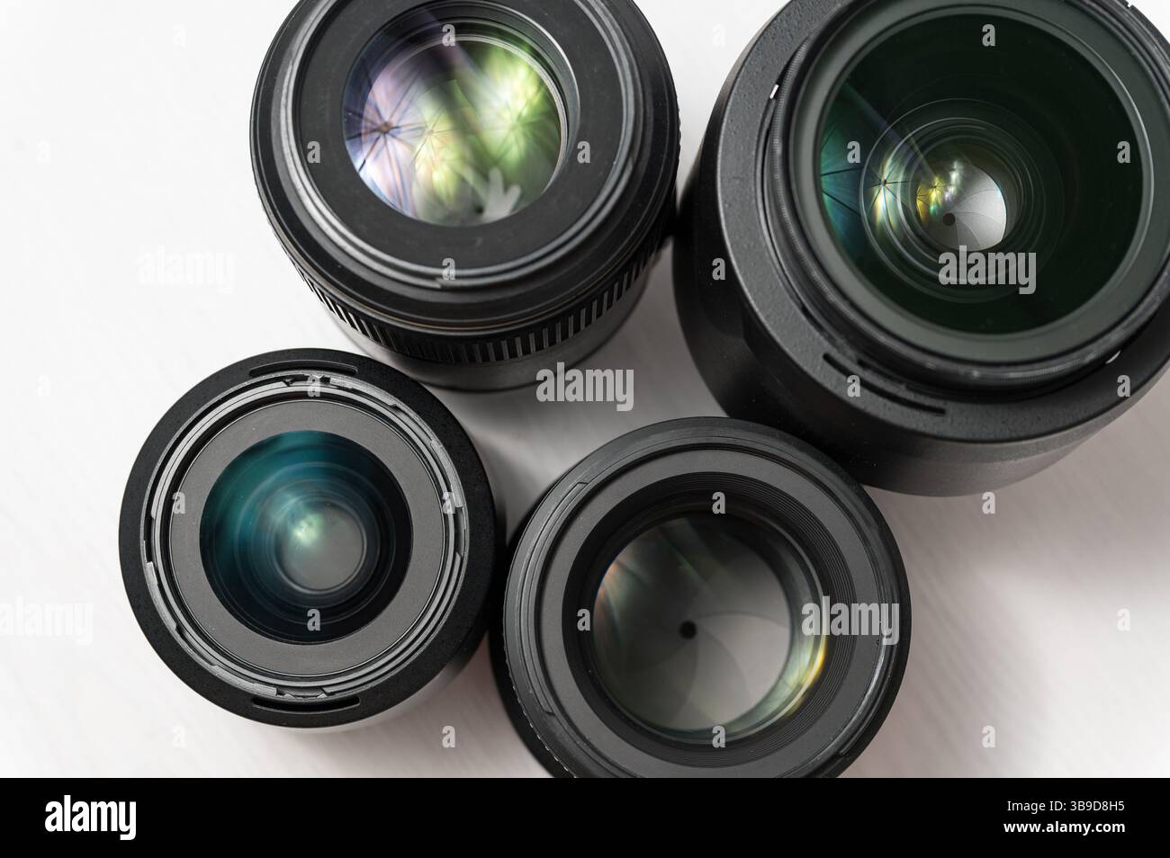 Close-up of four black camera lenses arranged on a white surface ...