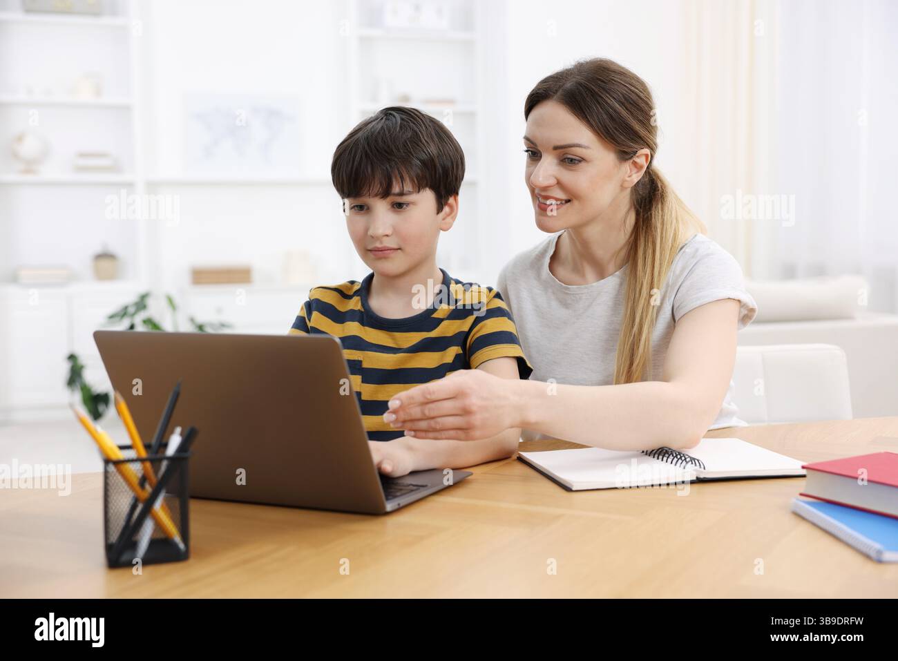 Mother helping her son with homework at wooden table indoors Stock Photo - Alamy