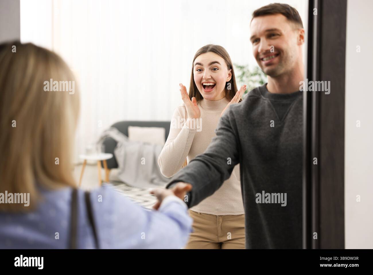 Lovely couple welcoming friend to their apartment Stock Photo - Alamy