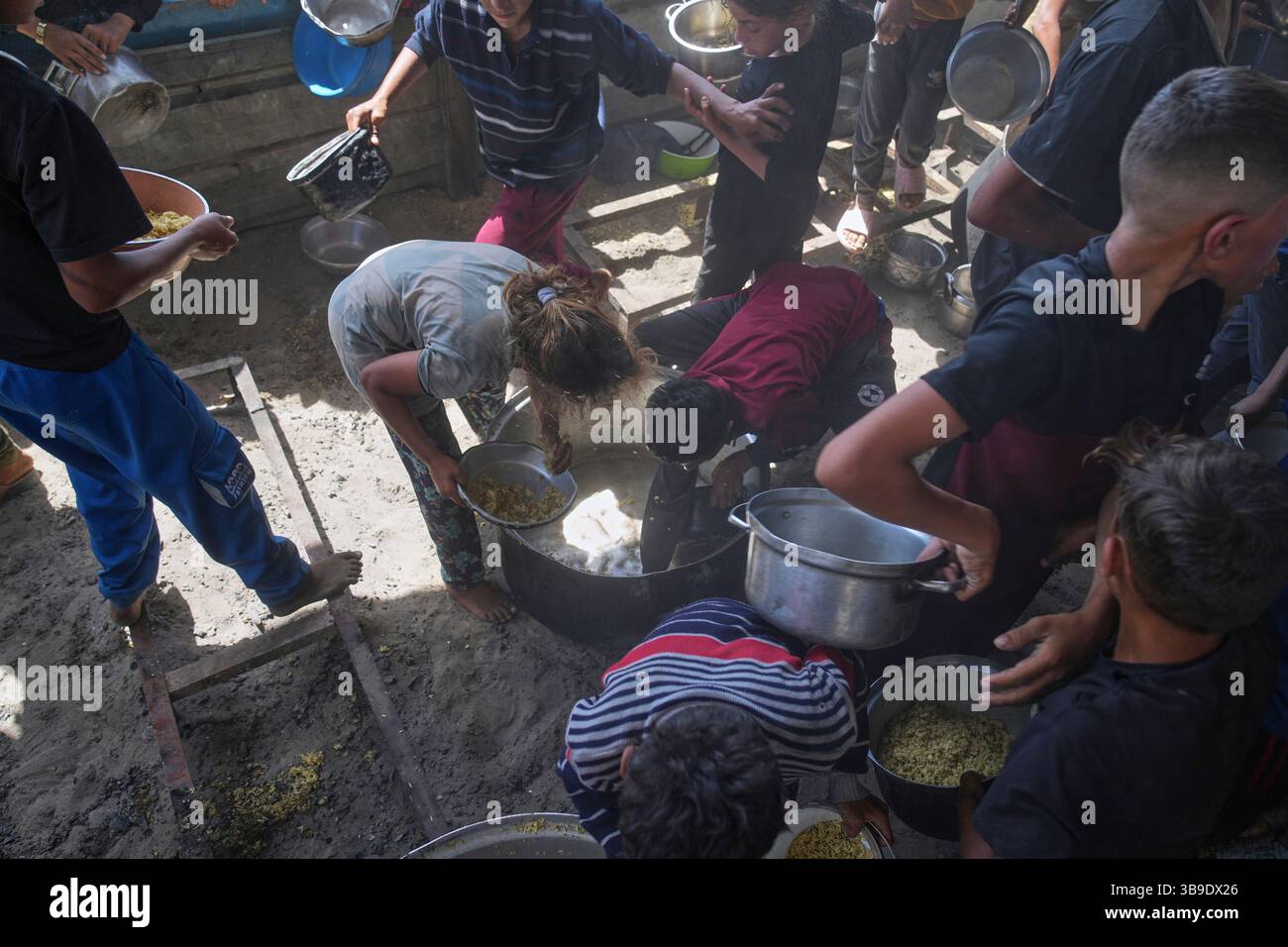 Palestinian children scrape a pot for leftover food after all meals ...