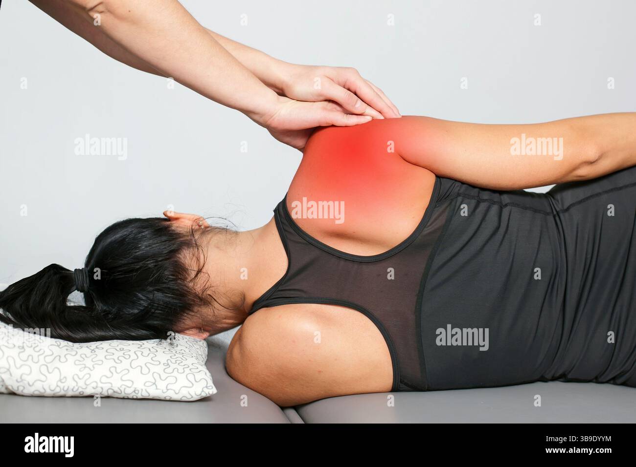 Shoulder pain treatment session. Woman lying on side. Therapist touching sore red shoulder ...