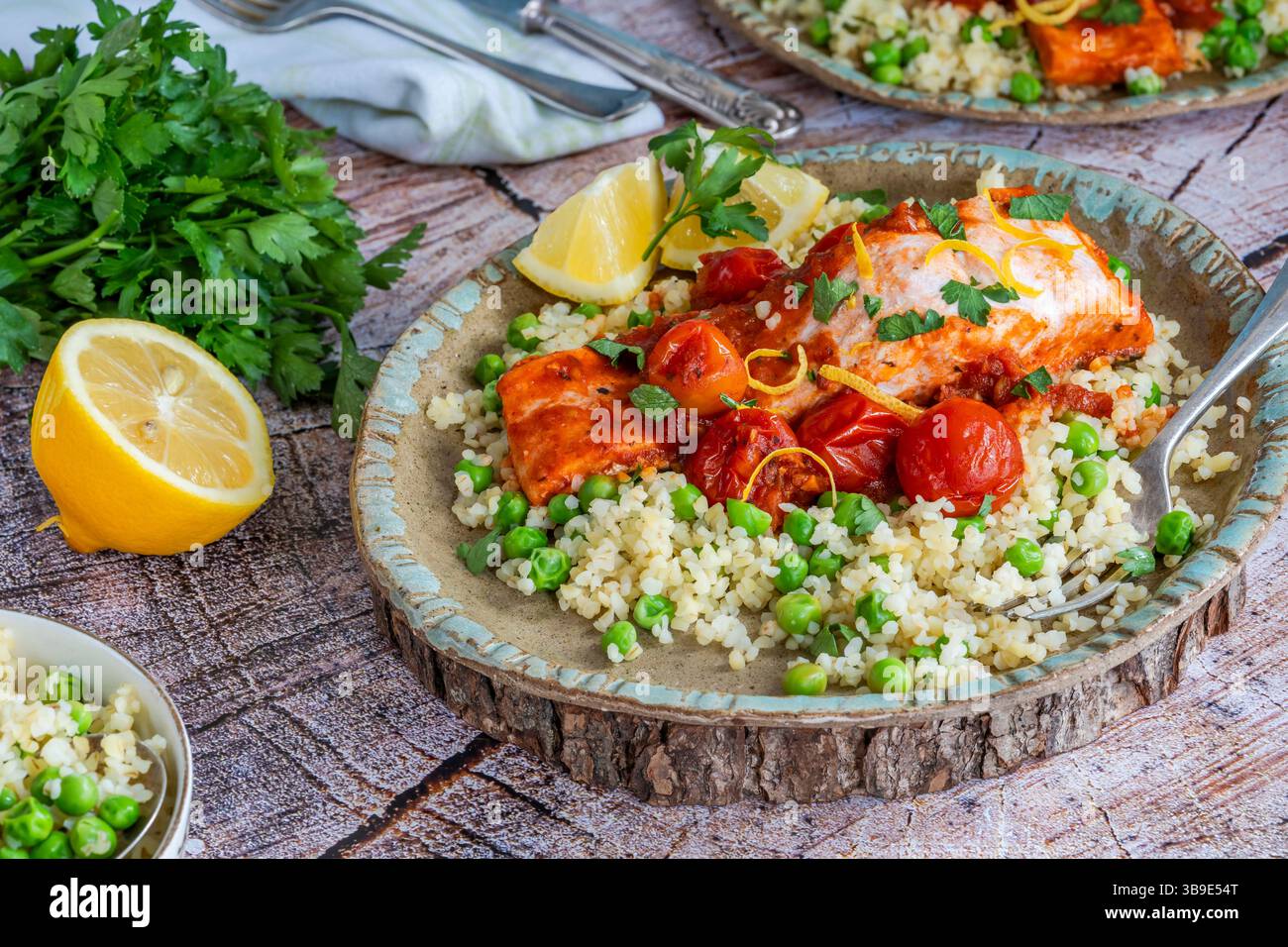 Harissa salmon with bulgur wheat, cherry tomatoes and green peas Stock ...