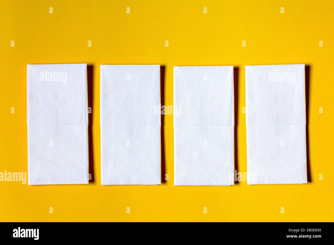 A neatly arranged stack of white dry tissues on a plain background. The ...