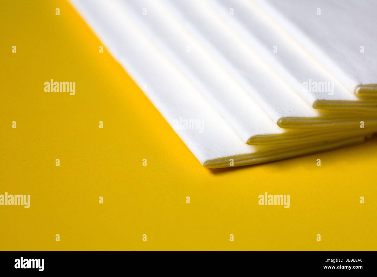 A neatly arranged stack of white dry tissues on a plain background. The ...