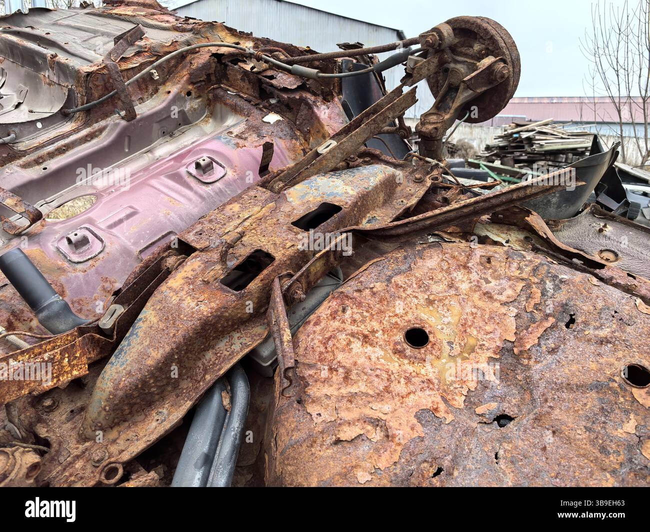 Rusting car parts and twisted metal rest in a desolate junkyard ...