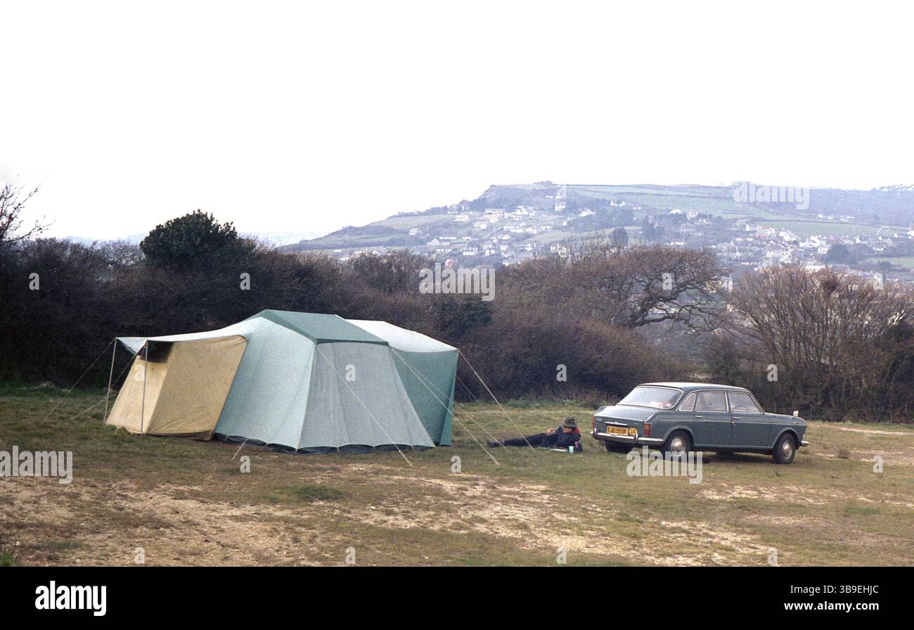 1970s, camping, outside in a field at the coast, a young man, mid to ...