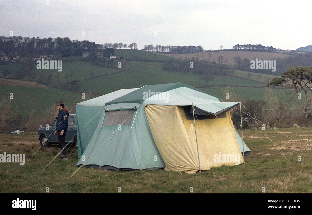 1970s, camping, outside in a field, a young man standing by his tent ...