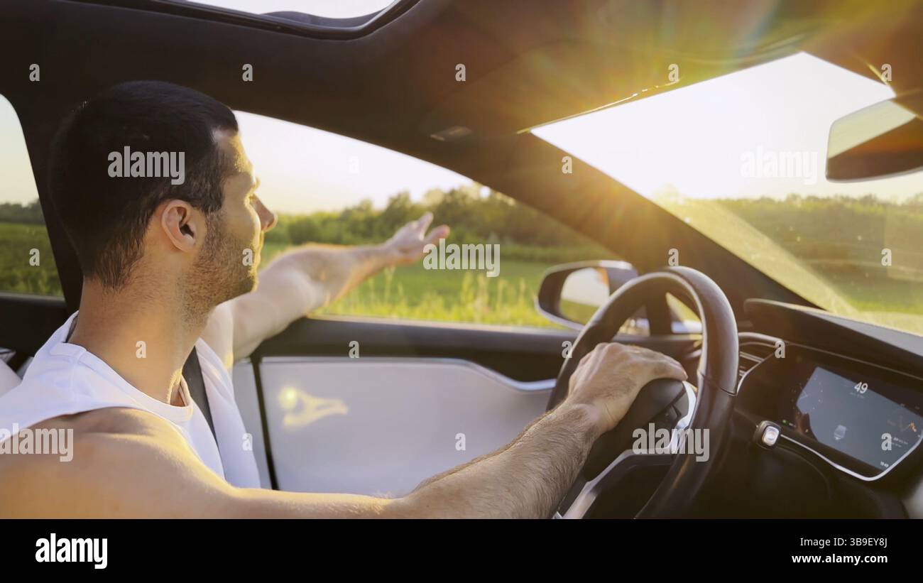 Profile of young handsome man driving a modern electric car with ...
