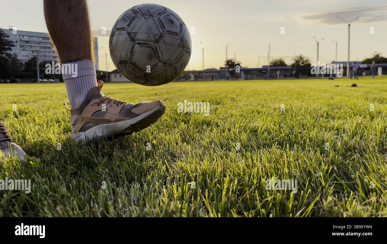 Male feet of professional footballer kicking ball at green field. Legs ...
