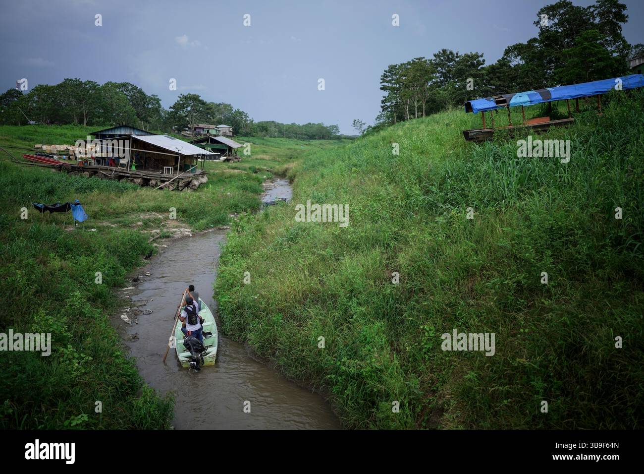FILE - People maneuver by boat through the low water levels of a ...