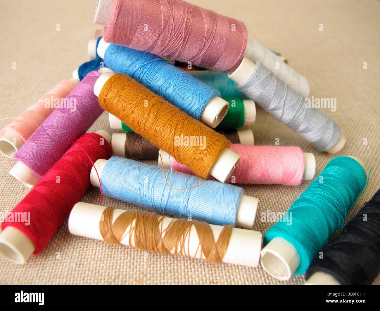 Sewing thread in different colours on fabric Stock Photo - Alamy