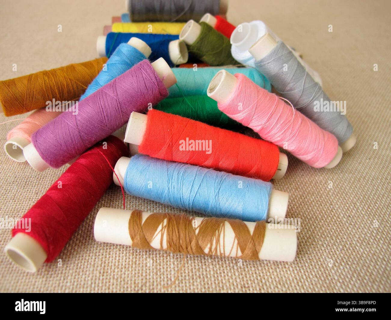 Sewing thread in different colours on fabric Stock Photo - Alamy