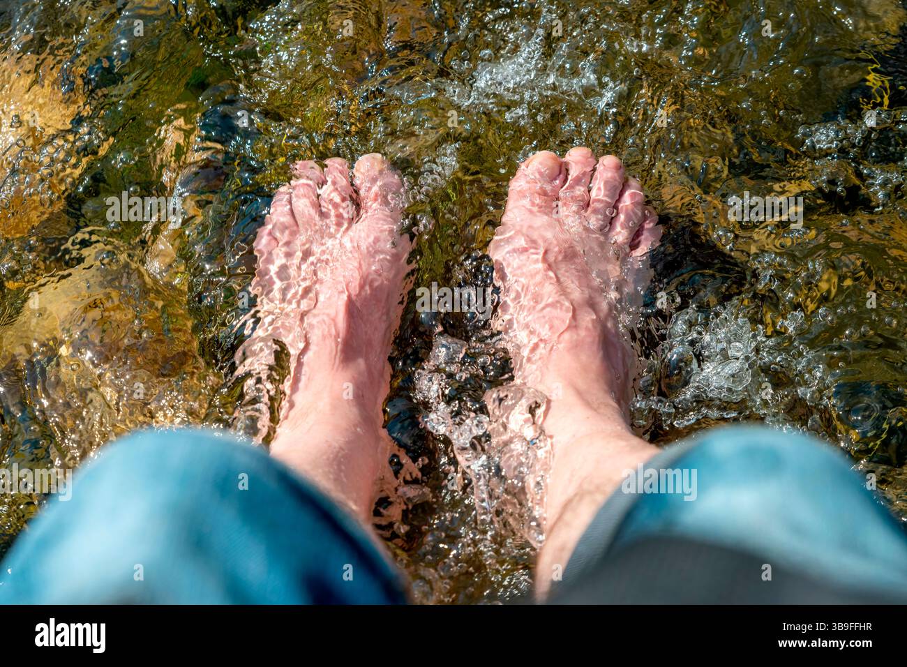 Flowing water between stones washes around the feet of a man Stock ...