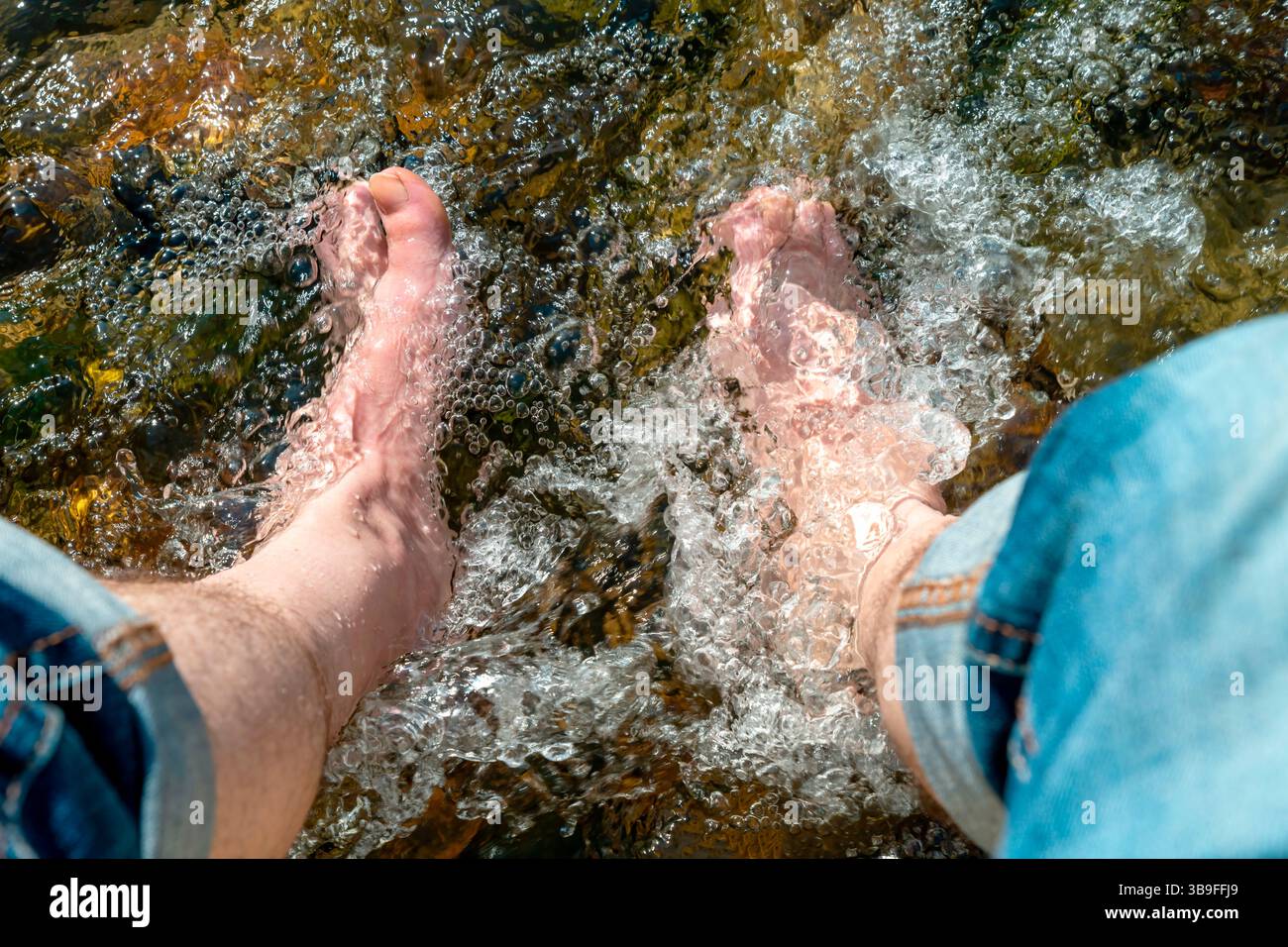 Running water between stones washes around the feet of a man Stock ...