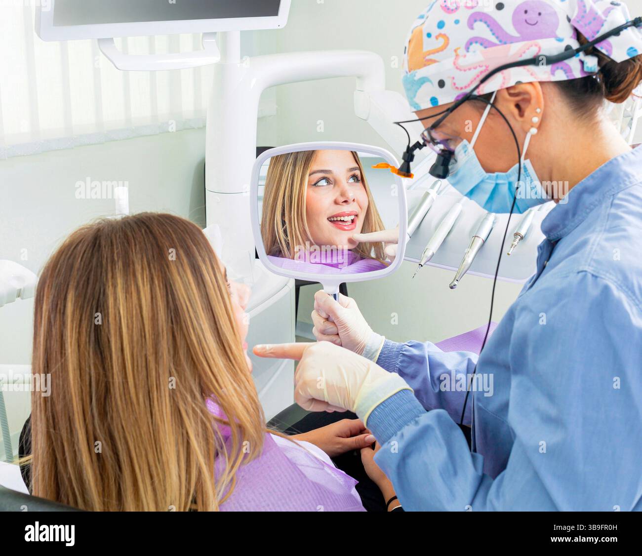 Dentist pointing at mirror, showing perfect smile to her patient after ...