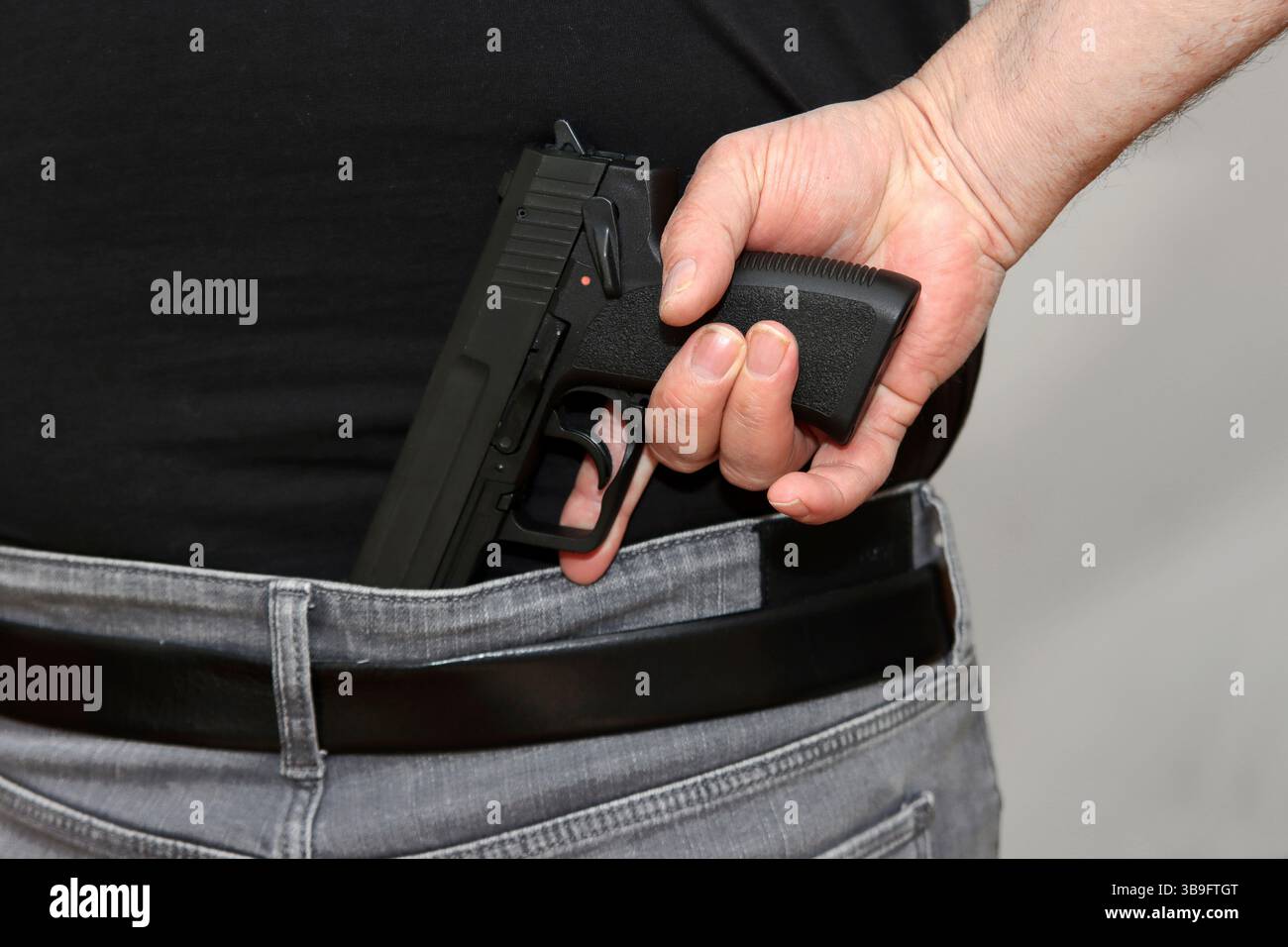 A man holds a pistol hidden behind his back Stock Photo - Alamy
