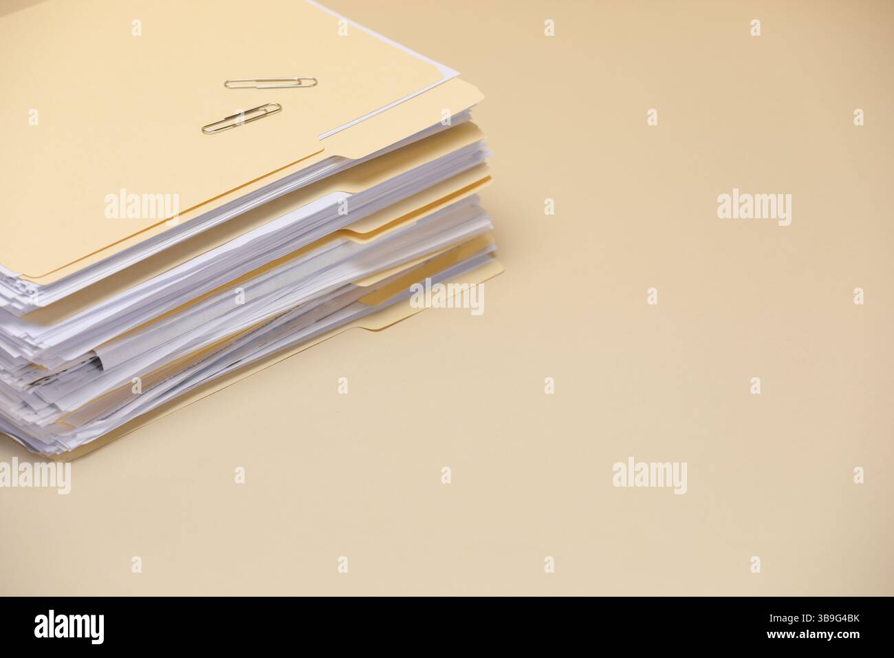 File folders with documents and paper clips on pale yellow background ...