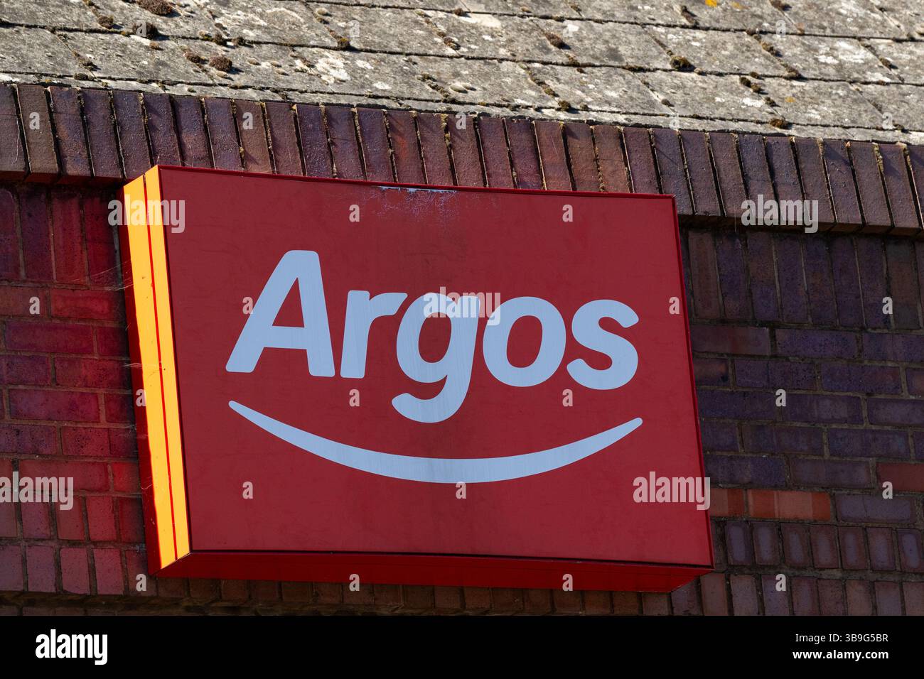 The image shows a red Argos store sign with white lettering, mounted on ...