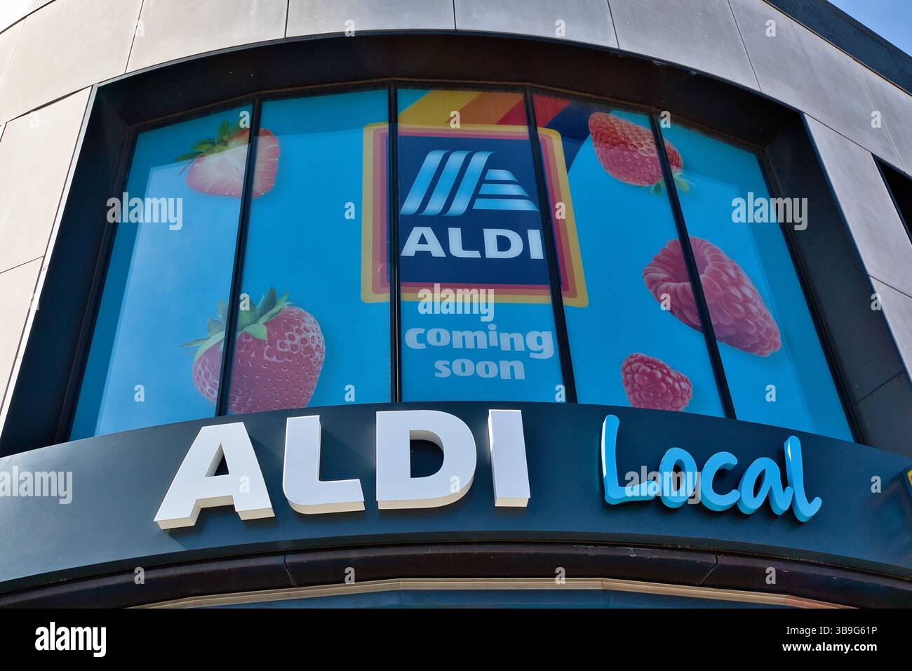 Building exterior with a large window display advertising an Aldi Local store, featuring images ...