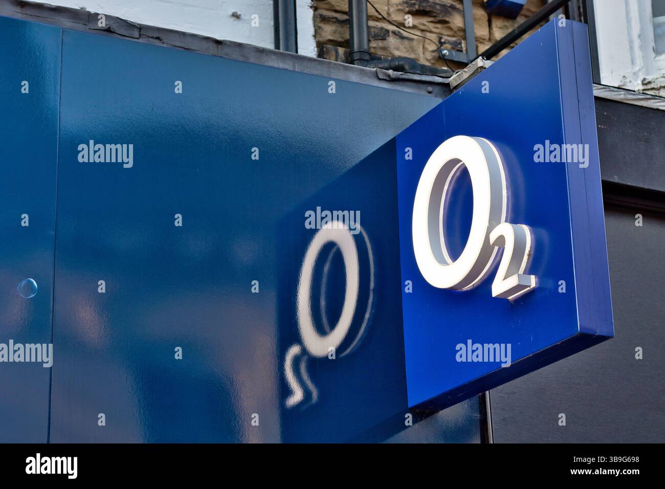 Close-up of a blue sign with the O2 logo; the logo is illuminated and ...