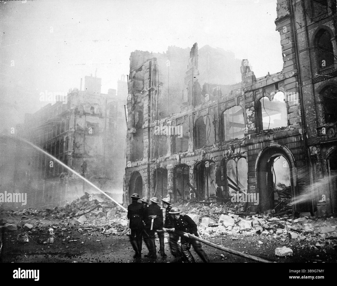 A group of firemen hosing burning ruins after an air raid in East ...
