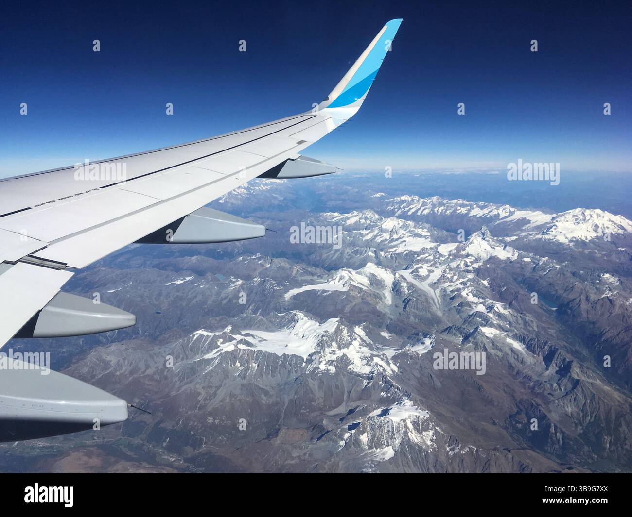 Aerial landscape view with airplane wing, flying over European Alps ...